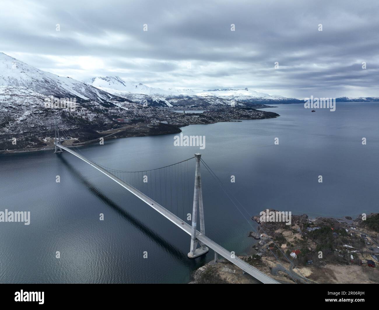 An aerial view of a a suspension bridge over water near snow-capped ...