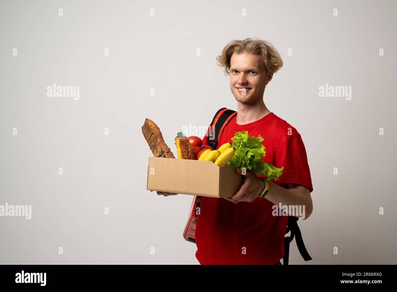 Courier man in red uniform with a thermal bag backpack hold craft paper ...