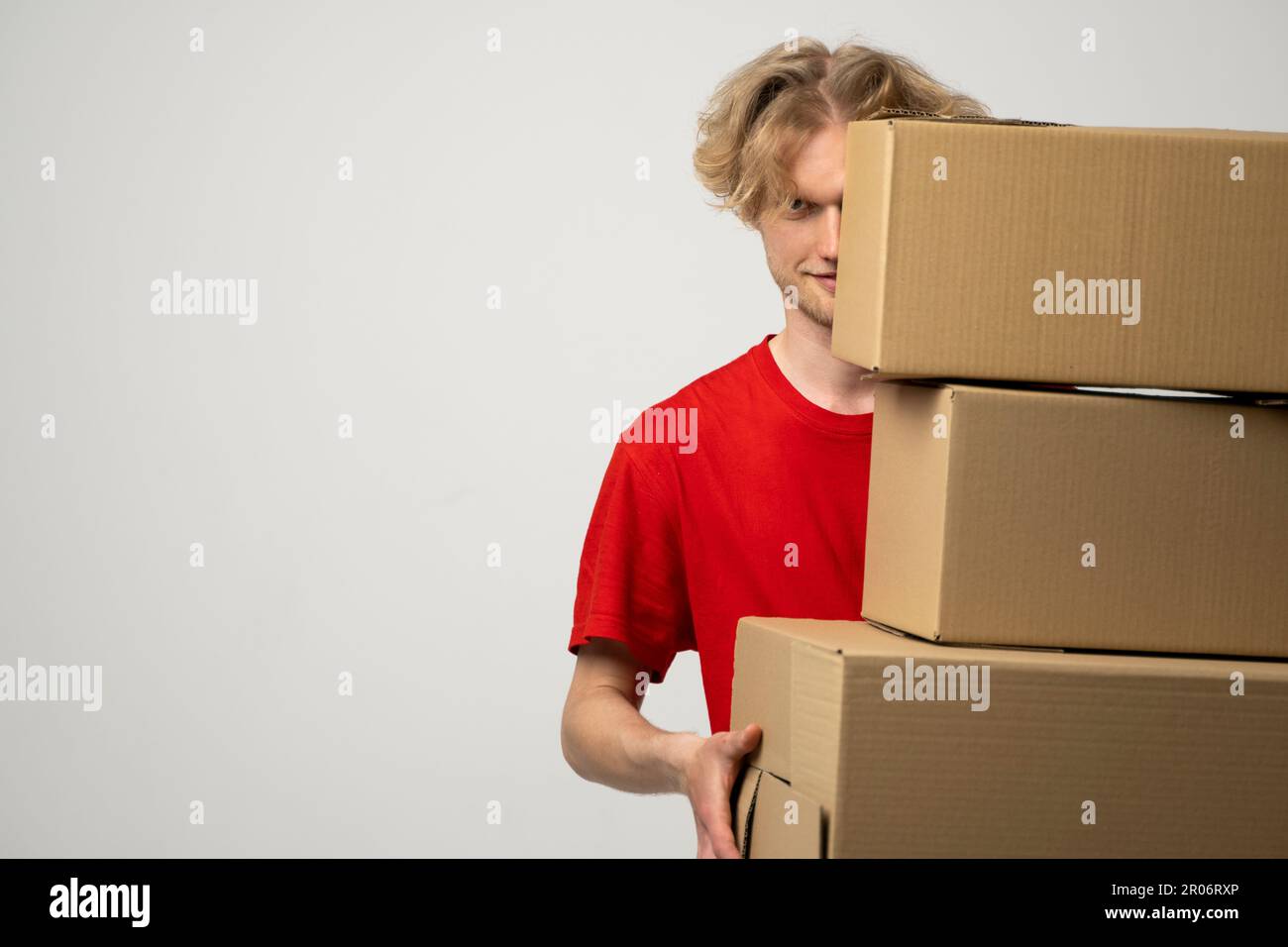 Courier in a red uniform holding a stack of cardboard boxes. Delivery ...