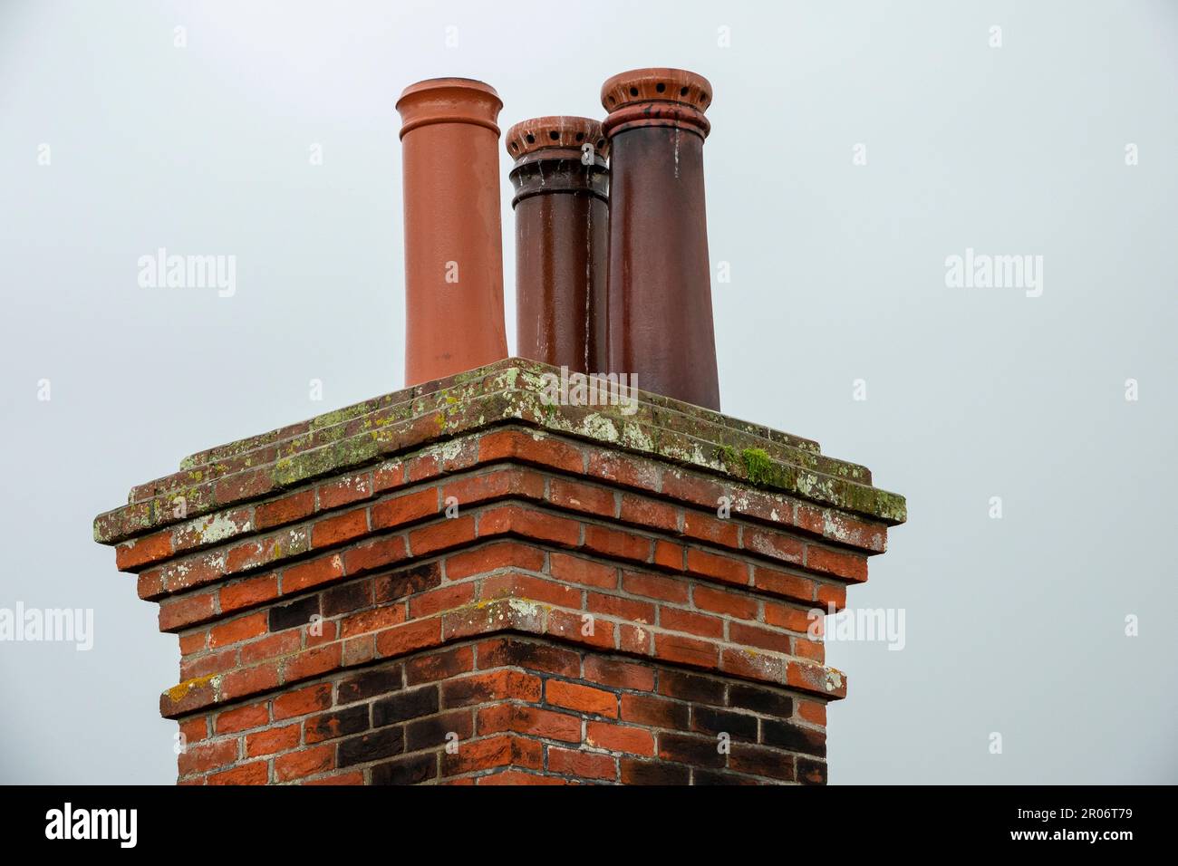 Red brick Victorian chimney stack with three red chimney pots wet and ...