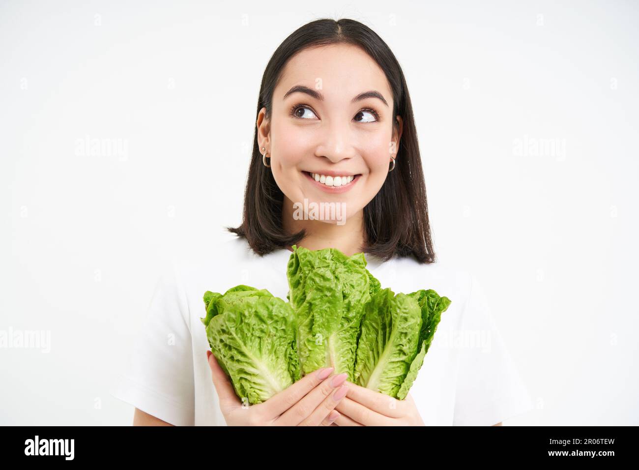 Vegetarian nutrition. Smiling happy young woman looks at her self grown ...
