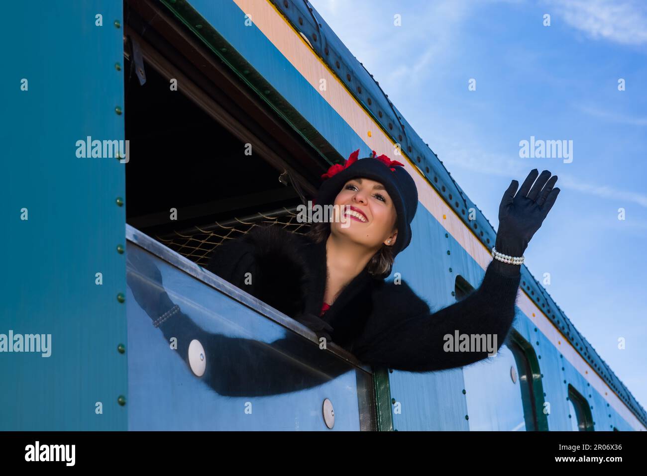 1920s woman wearing fur coat and cloche hat hanging out of the window ...