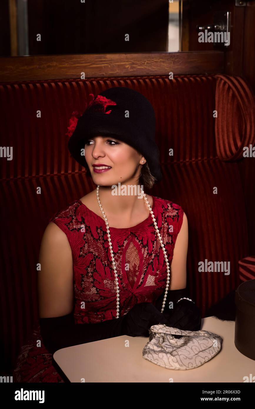 Attractive 1920s woman in red flapper dress and cloche hat posing in ...