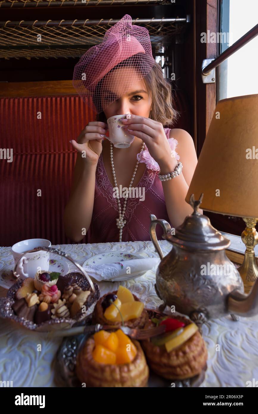 Reenactment scene of a 1920s flapper dress lady enjoying high tea in an ...
