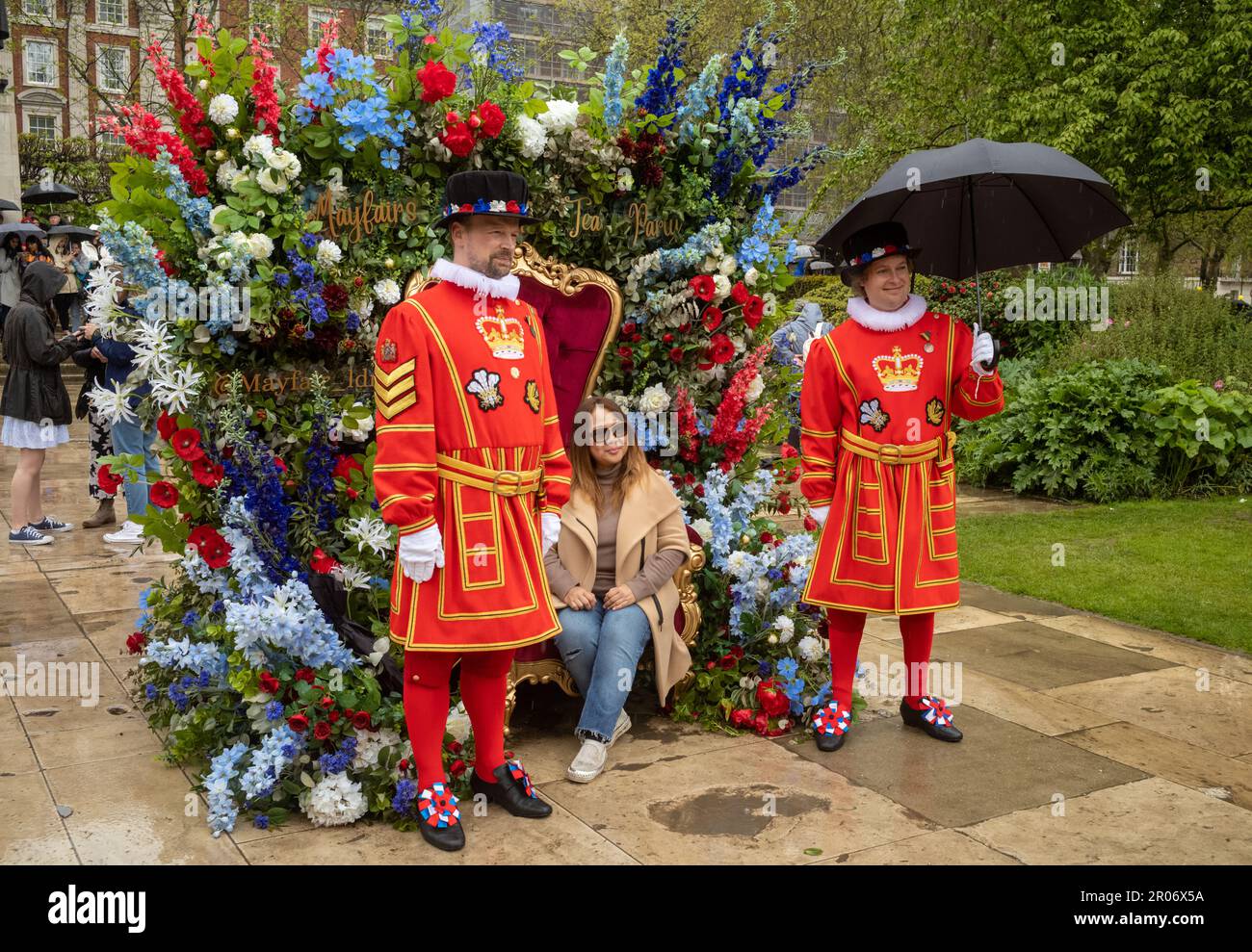 A woman poses on a mock throne with two men dressed as beefeaters in ...