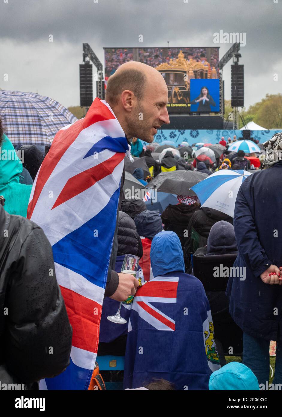 A man with a bald head stands in a large crowd of people, holding a ...