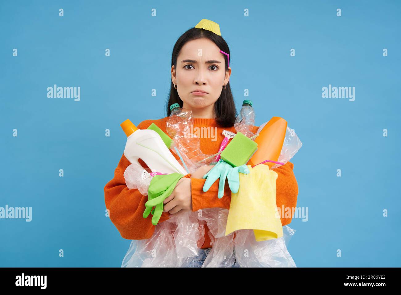 Angry young woman, holding empty plastic bottles and garbage, sorting ...