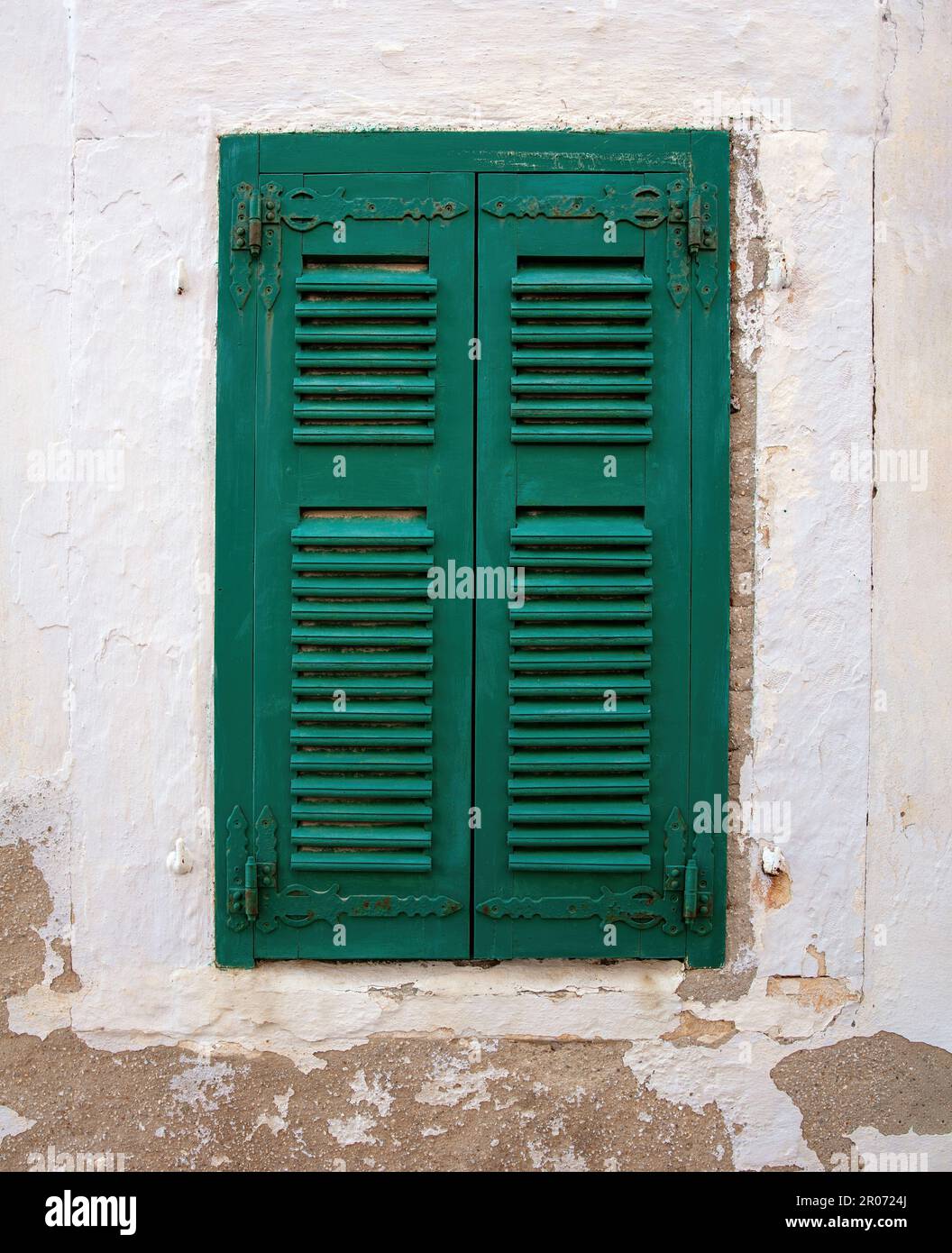 Old fashioned window with closed green wooden shutter on faded, peeled ...