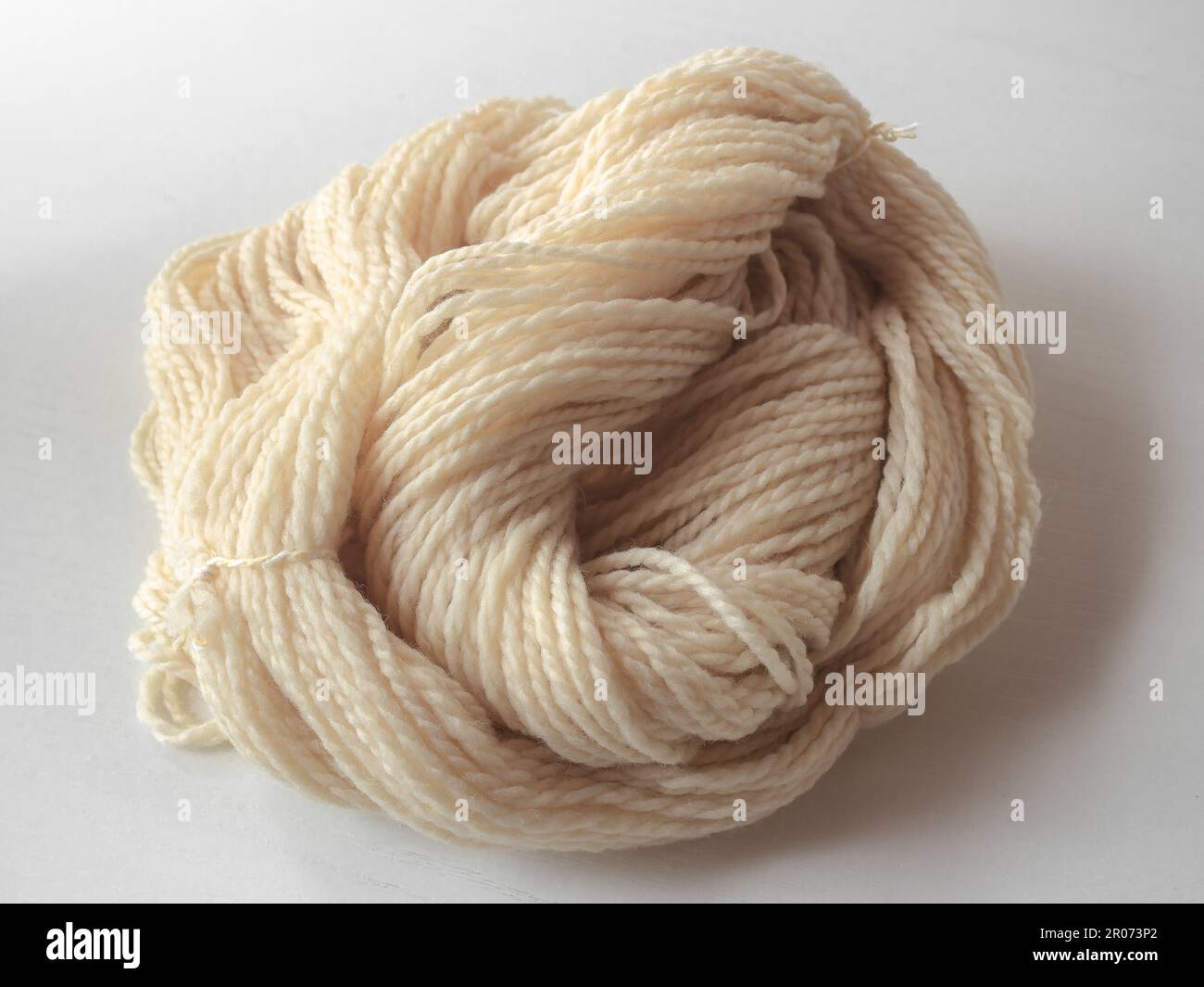 A closeup of a yarn of beige thread on a white background Stock Photo ...