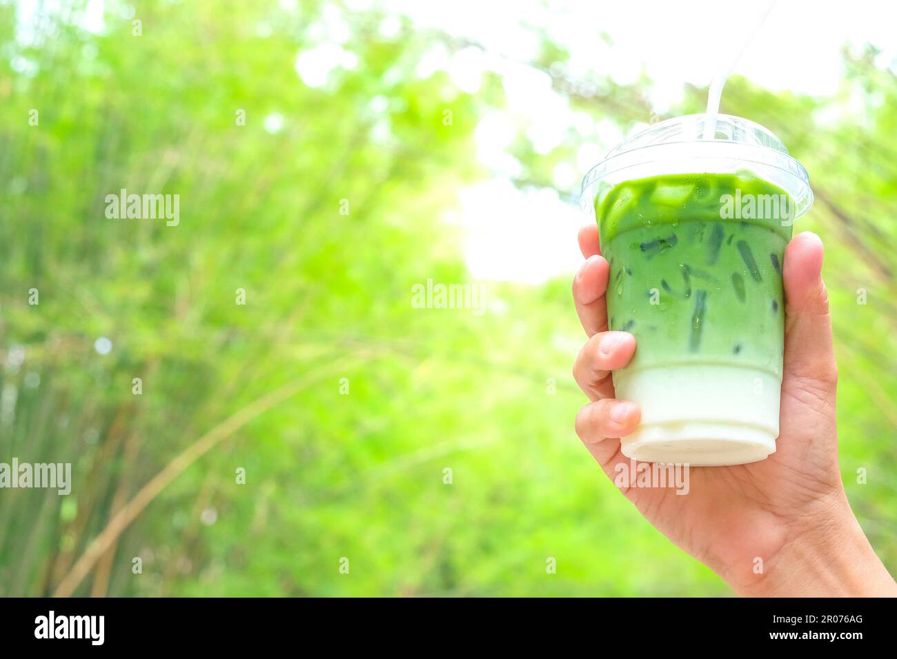 Woman hand holding the glass iced matcha latte green tea coffee on ...