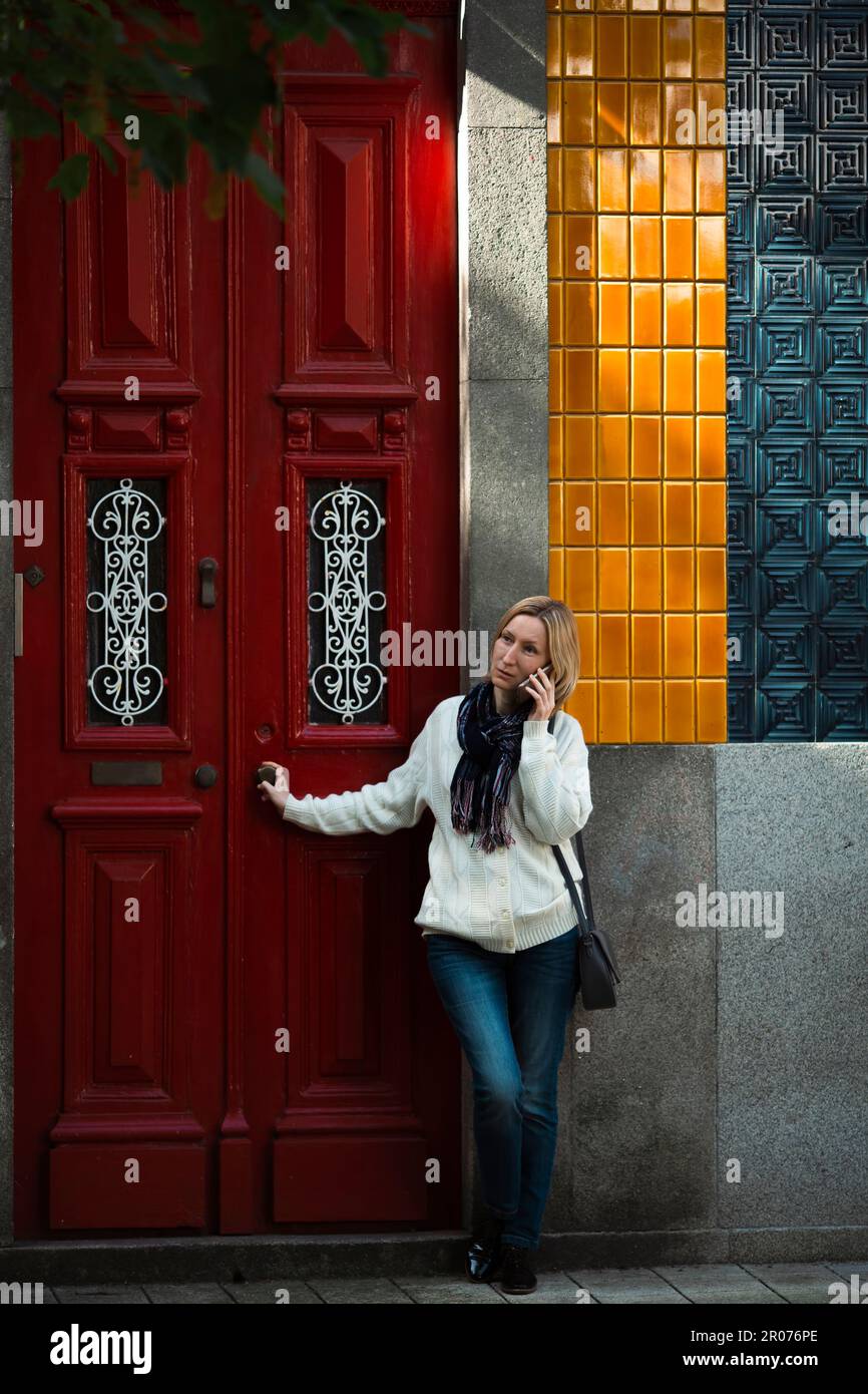 A woman talking on the phone outside the door of a traditional house in ...