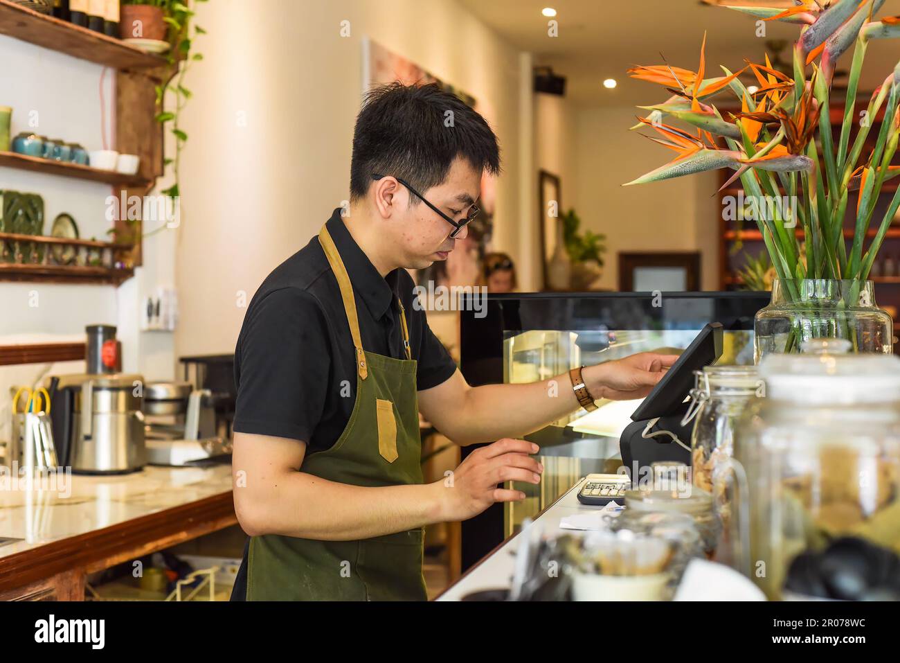 Vietnamese waiter working in counter with cashier machine in a cafe ...