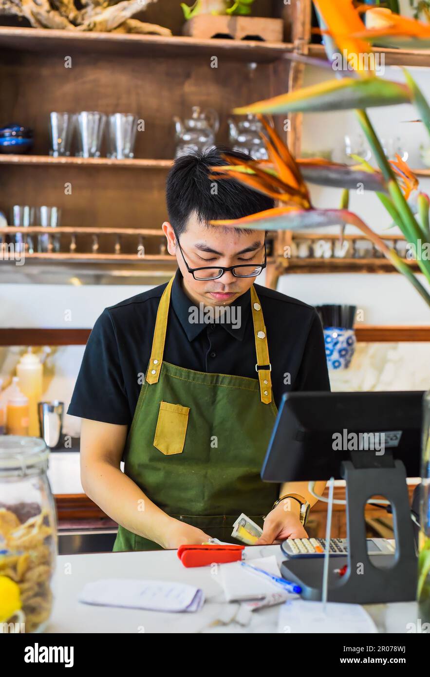 Vietnamese waiter working in counter with cashier machine in a cafe ...