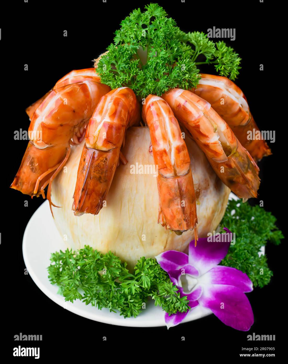 Orange shrimps inside of coconut with sauce isolated on black ...