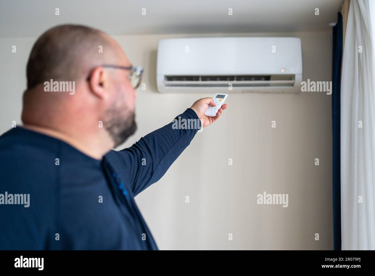 Overweight exhausted man using remote control to switch on air ...