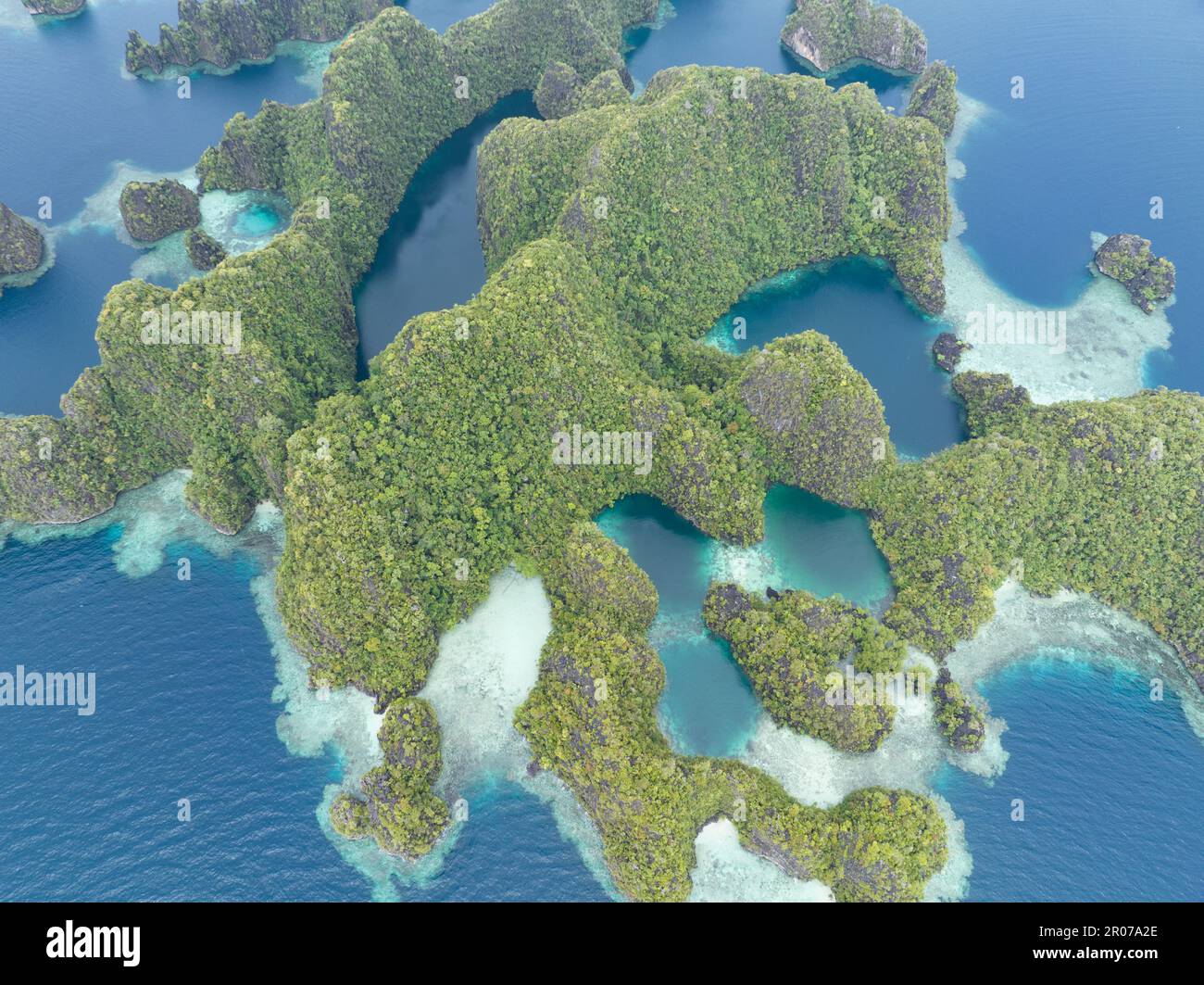 Coral reefs surround the rugged limestone islands that rise from Raja ...