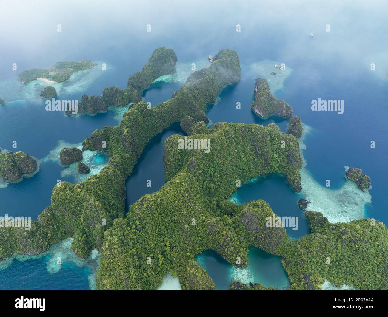 Coral reefs surround the rugged limestone islands that rise from Raja ...