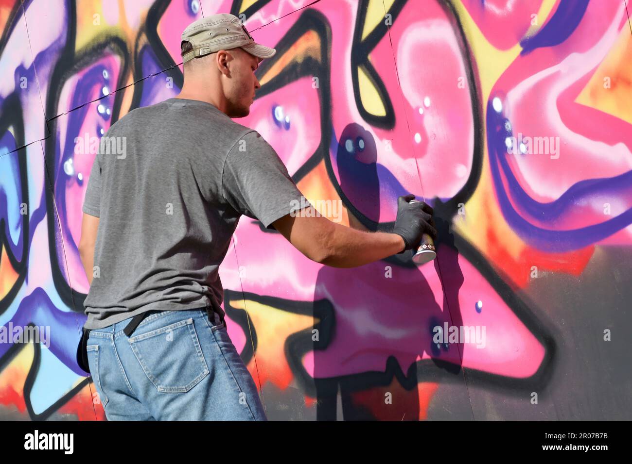 Young caucasian male graffiti artist drawing big street art painting in ...