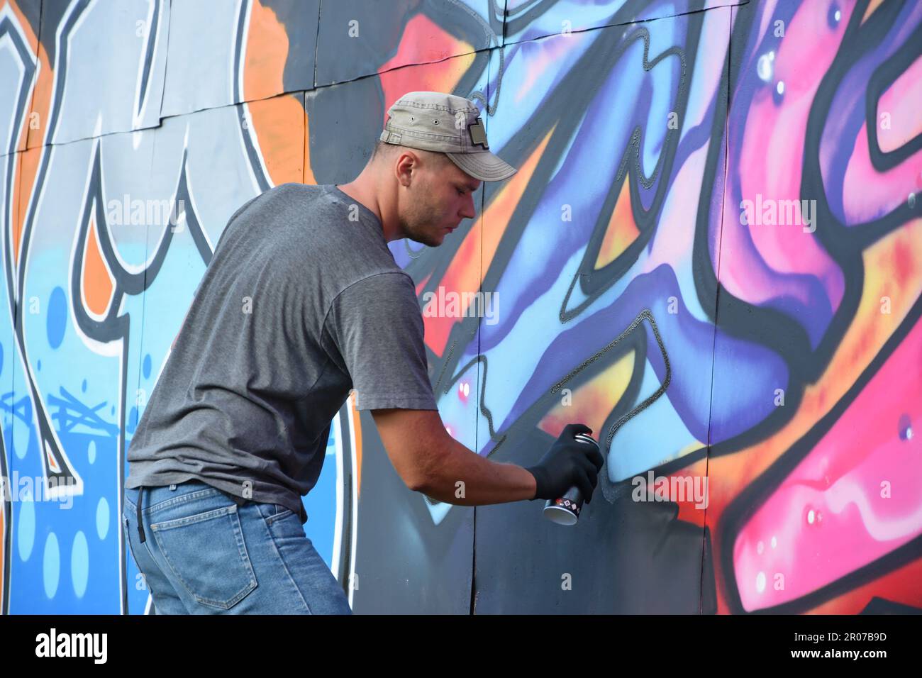 Young caucasian male graffiti artist drawing big street art painting in ...