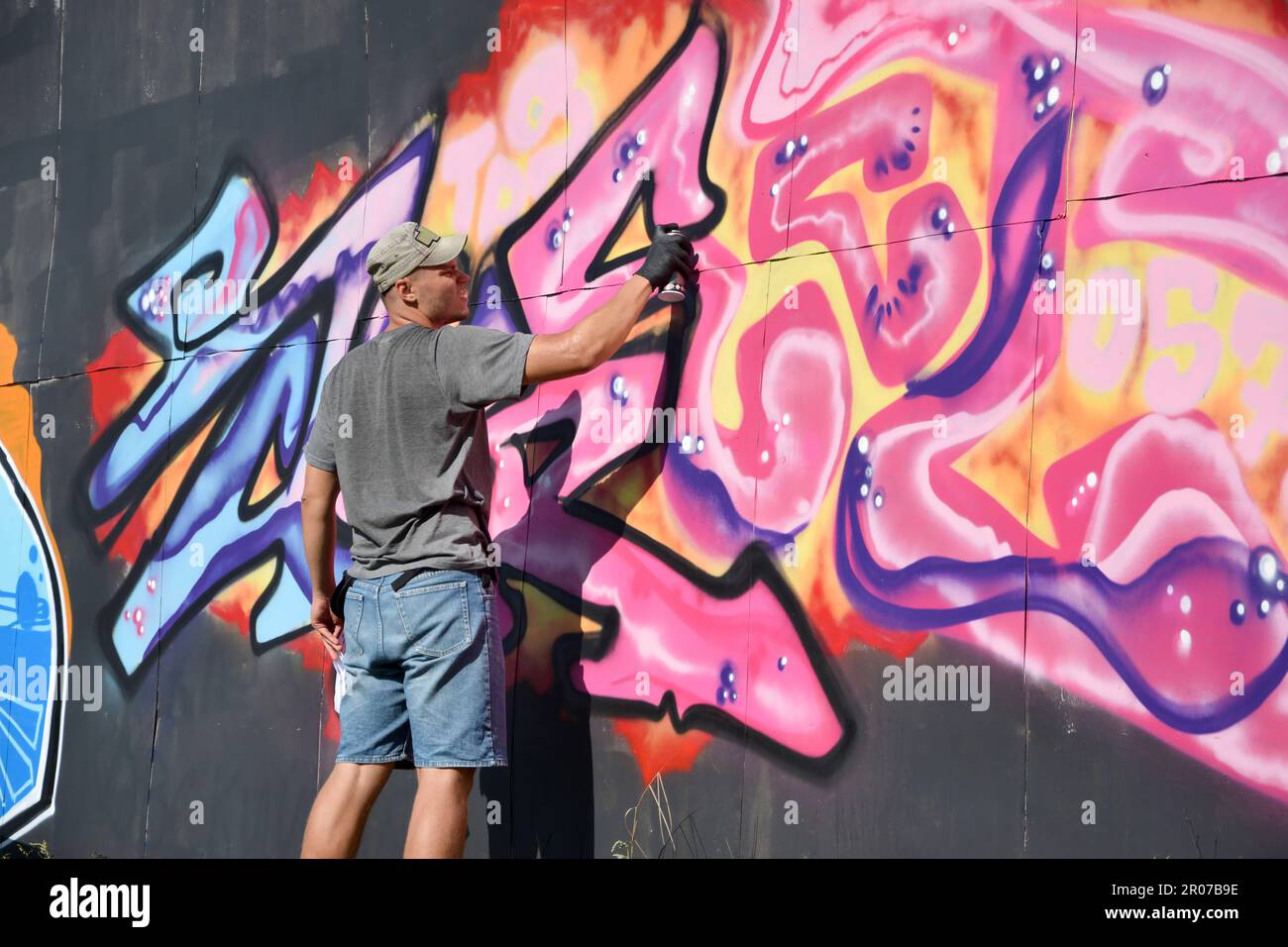 Young caucasian male graffiti artist drawing big street art painting in ...