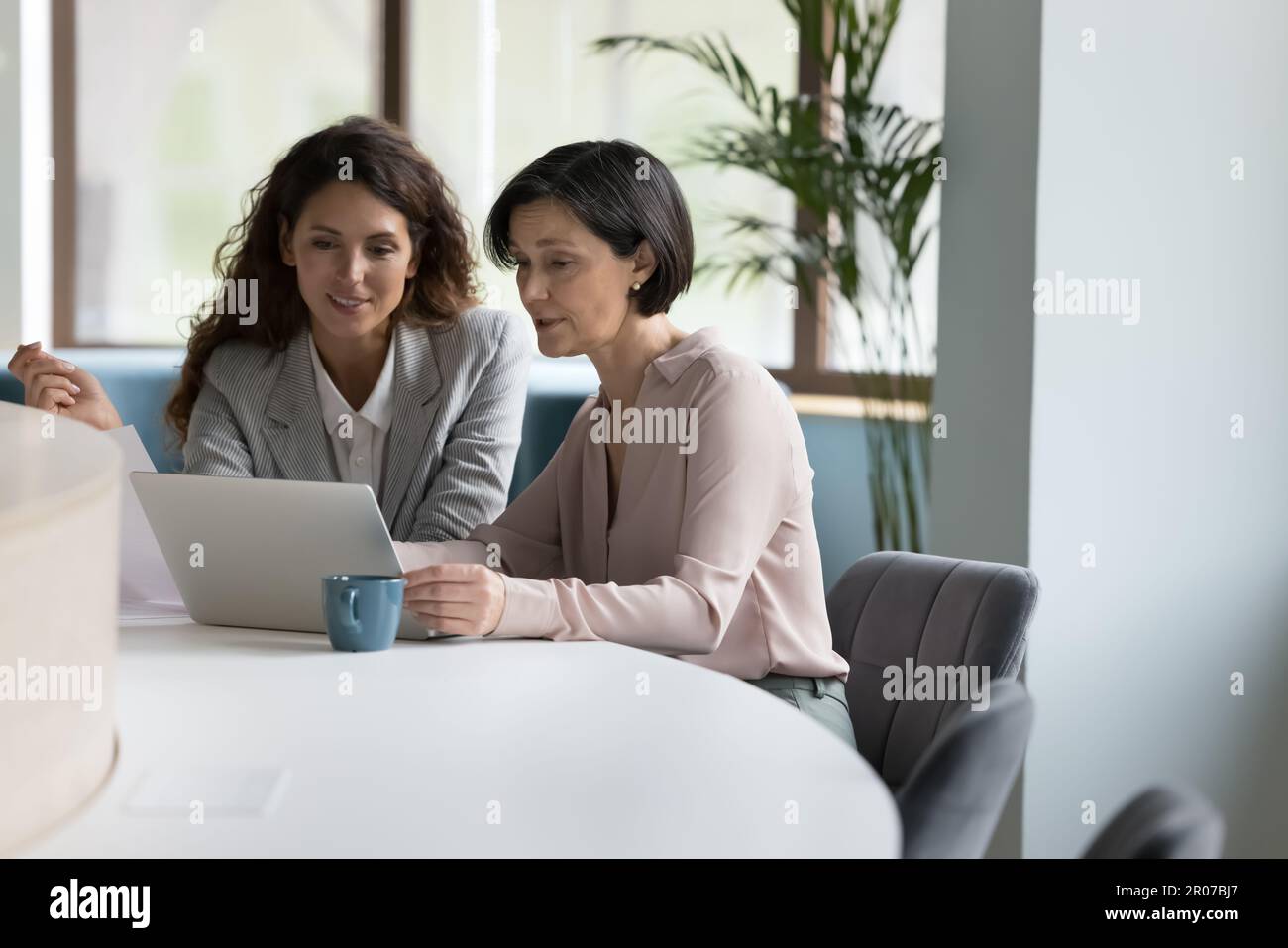Two women colleagues working together use computer Stock Photo - Alamy