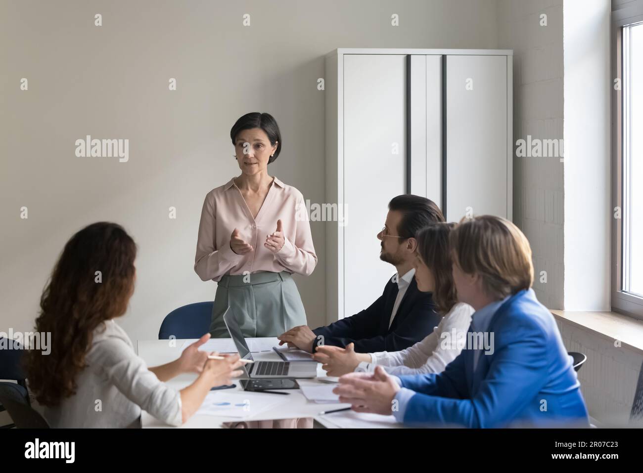 Executive team listen to mature female CEO presenting project plan ...