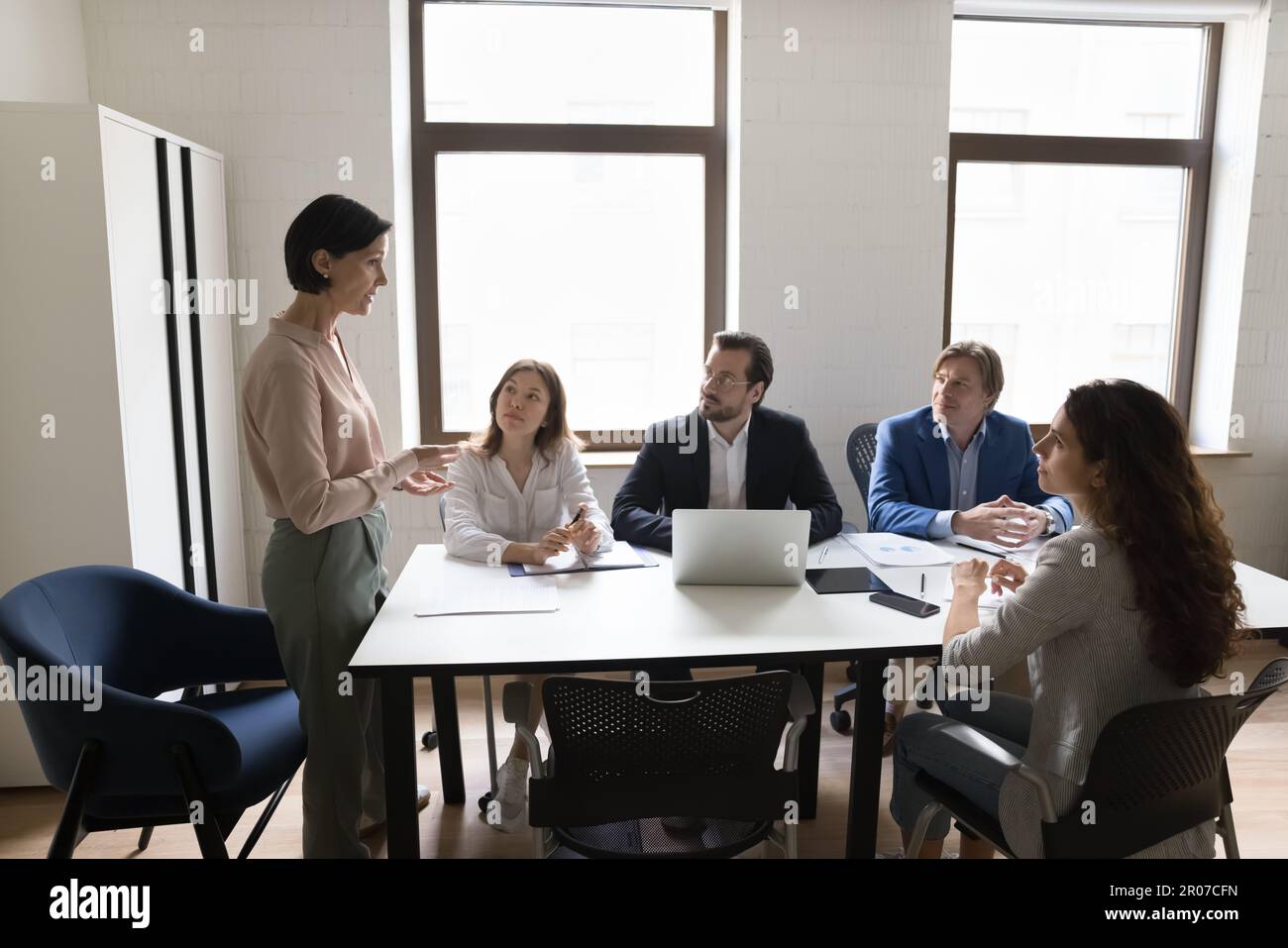 Mature female boss make speech standing in front of clients Stock Photo ...