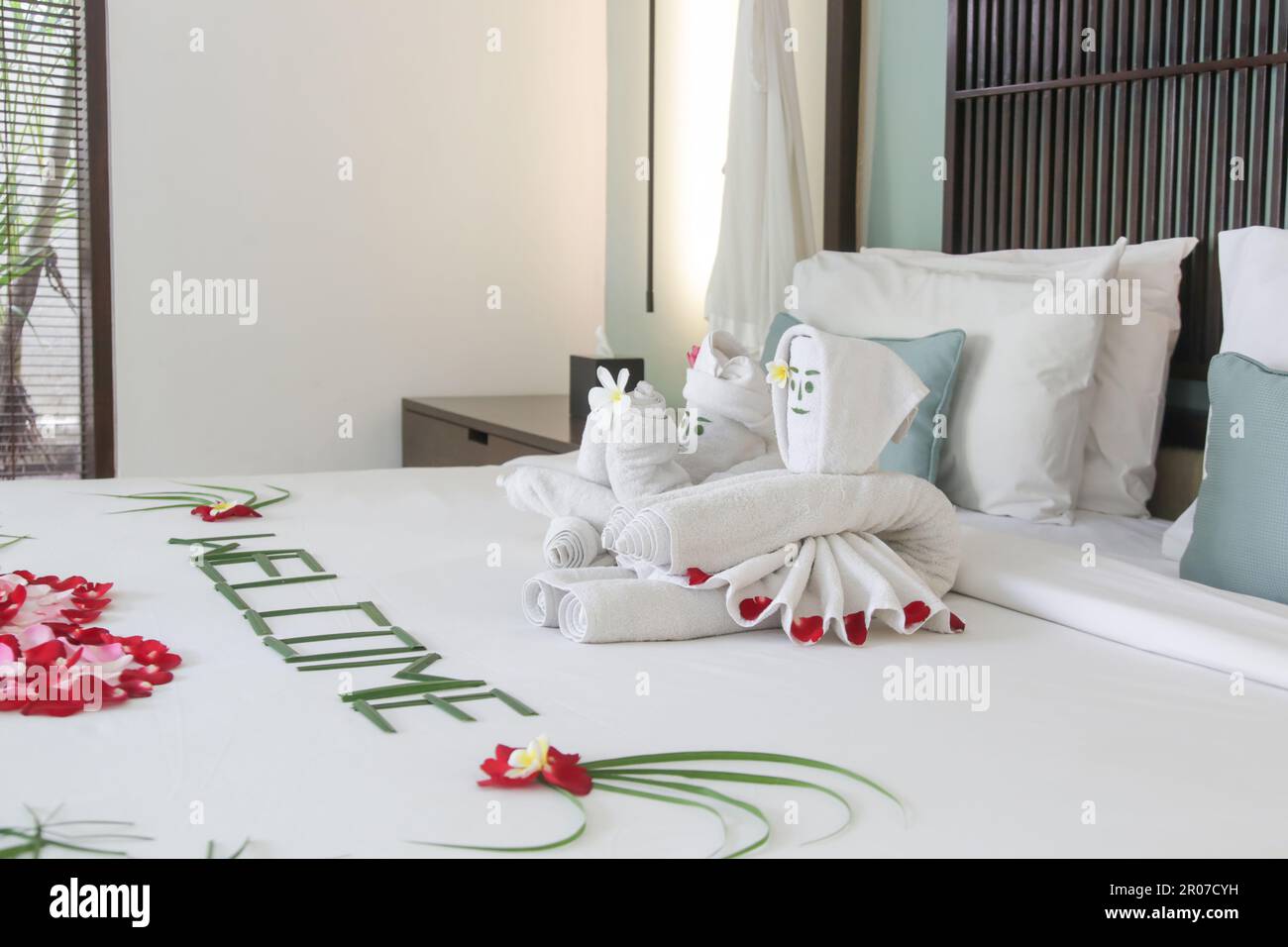 Welcome flowers and towels arrangement on the bed in luxury hotel on ...