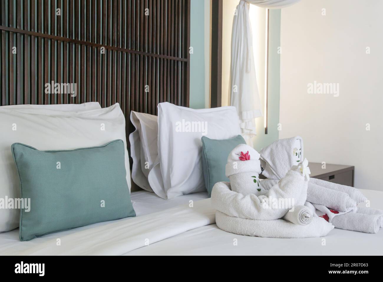 Welcome flowers and towels arrangement on the bed in luxury hotel on ...