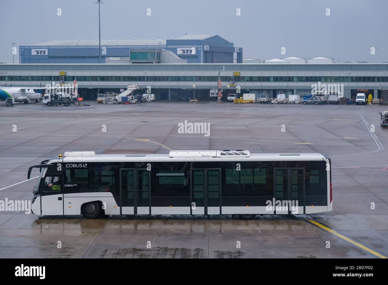 Empty white airport bus in a rainy day. Aviation service at Manchester ...