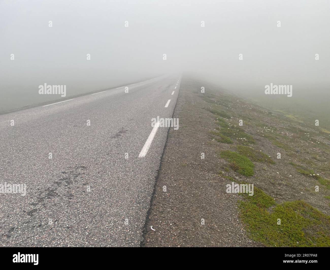 Narrow, traffic-free, road in dense fog, barren landscape, Vardoe ...