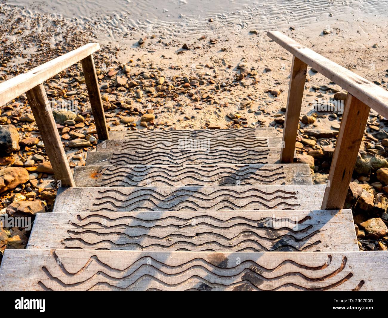 Path down to the beach. Empty wooden steps way on sandy beach, rock and ...