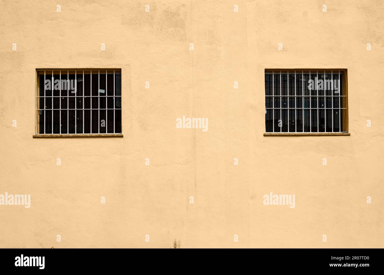 Wall. External yellow wall with two small windows with bars Stock Photo ...