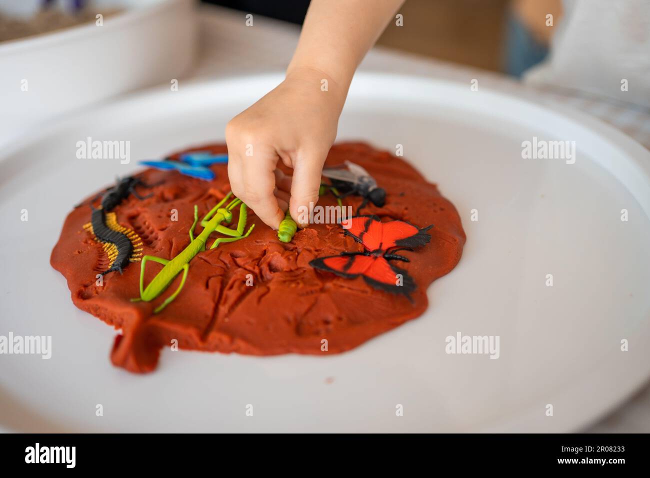 A little girl playing with plasticine and toys insects. Sensory ...