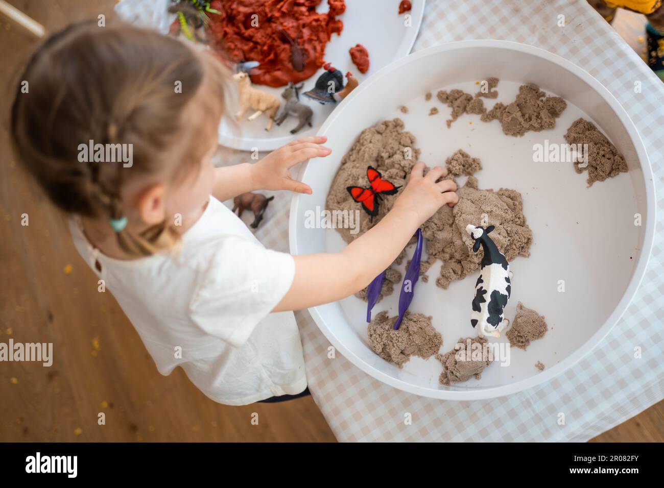 Little girl playing with kinetic sand and toys insect. Sensory ...