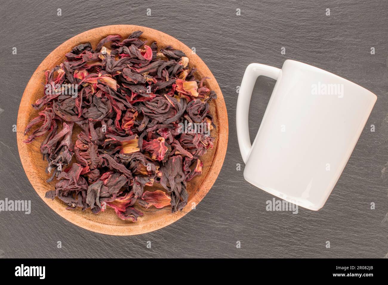 Dry fragrant karkade tea with wooden saucer and white ceramic cup on ...