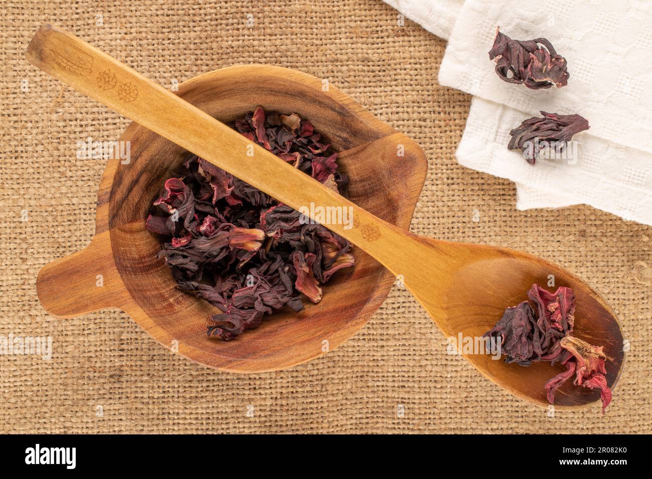 Dry fragrant karkade tea with wooden cup and wooden spoon on jute cloth ...