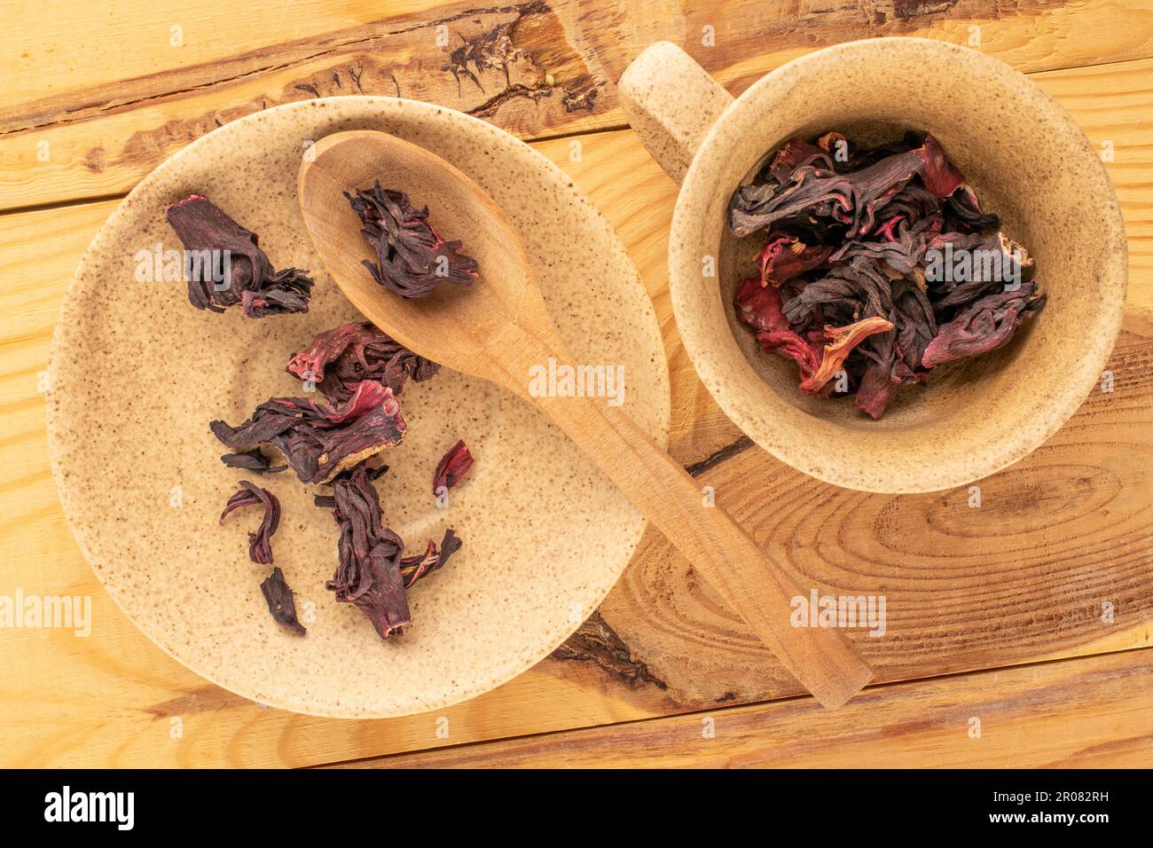 Dry aromatic karkade tea with ceramic cup, saucer and wooden spoon on ...