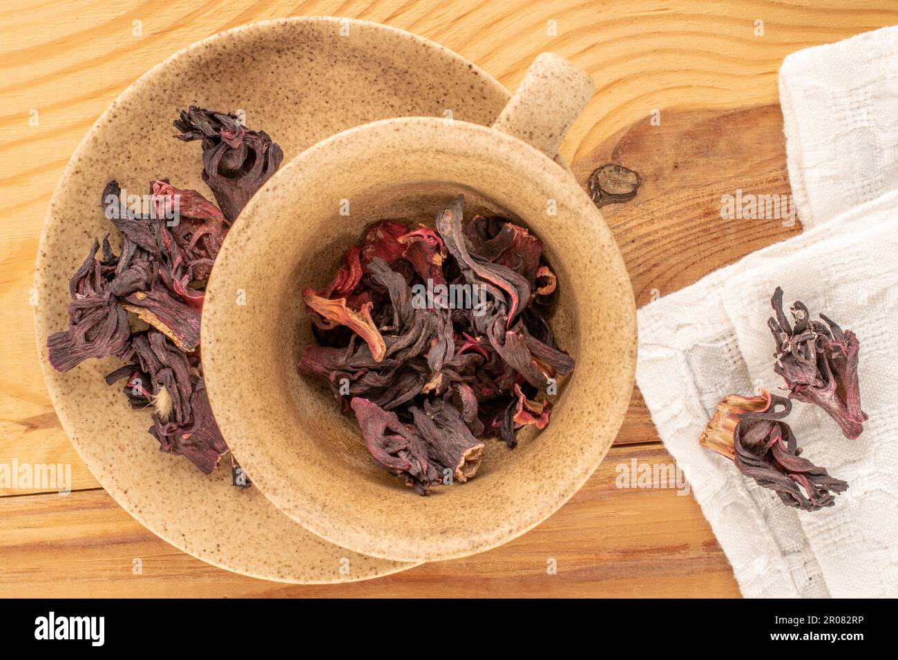 Dry fragrant karkade tea with ceramic cup and saucer on wooden table ...