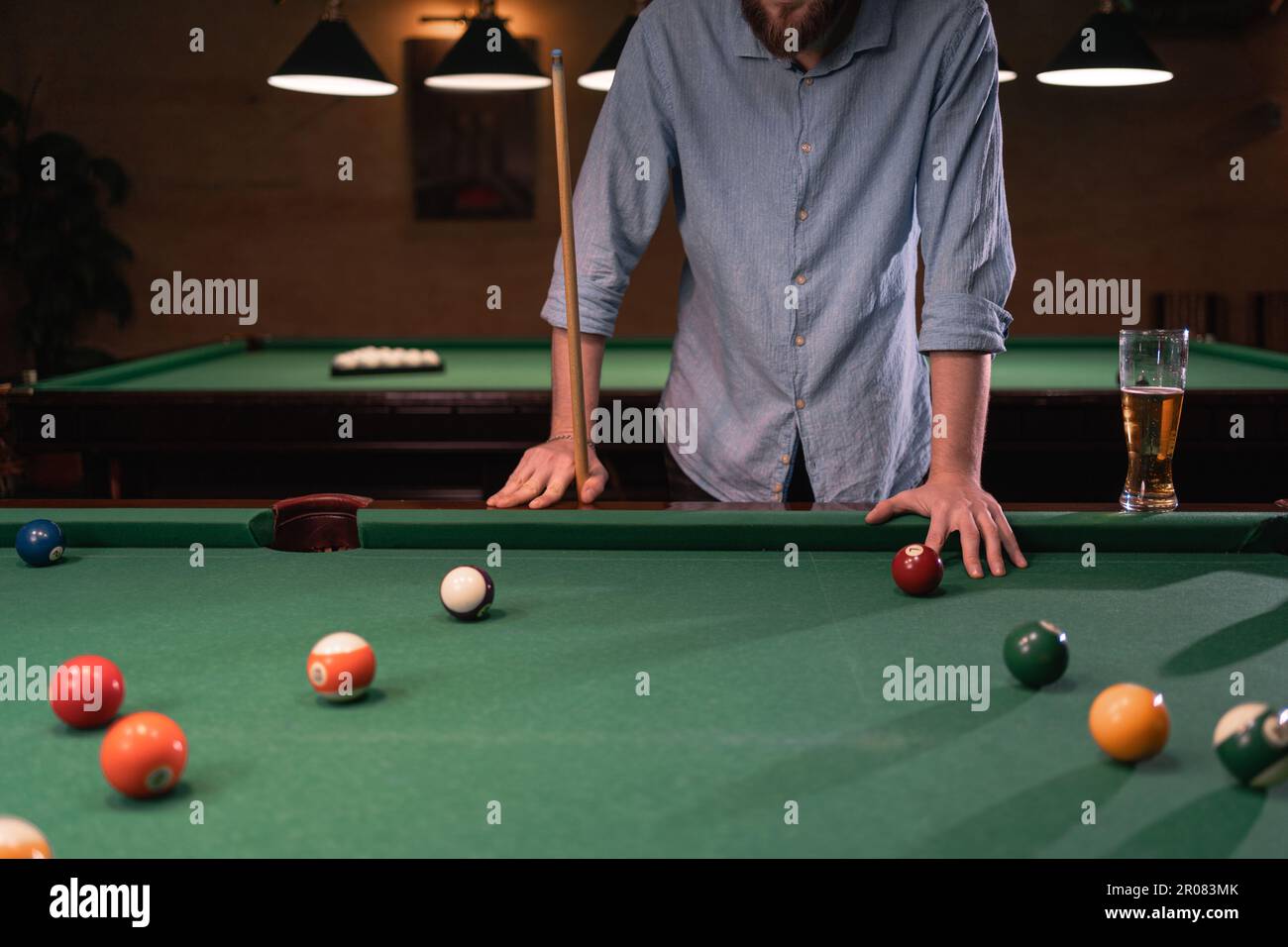 Unrecognizable thoughtful man plays billiards with balls and cue ...
