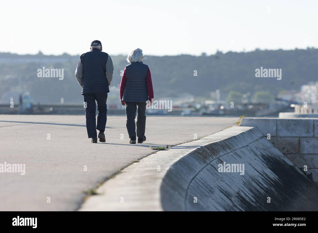 An elderly couple walks along the embankment near a concrete slope ...