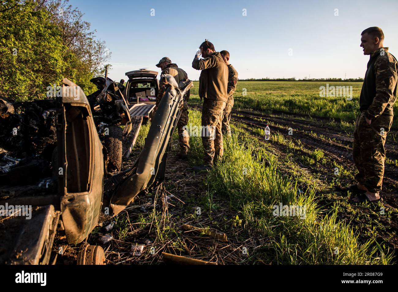 Ukrainian soldiers loading a car damaged by artillery fire in the ...