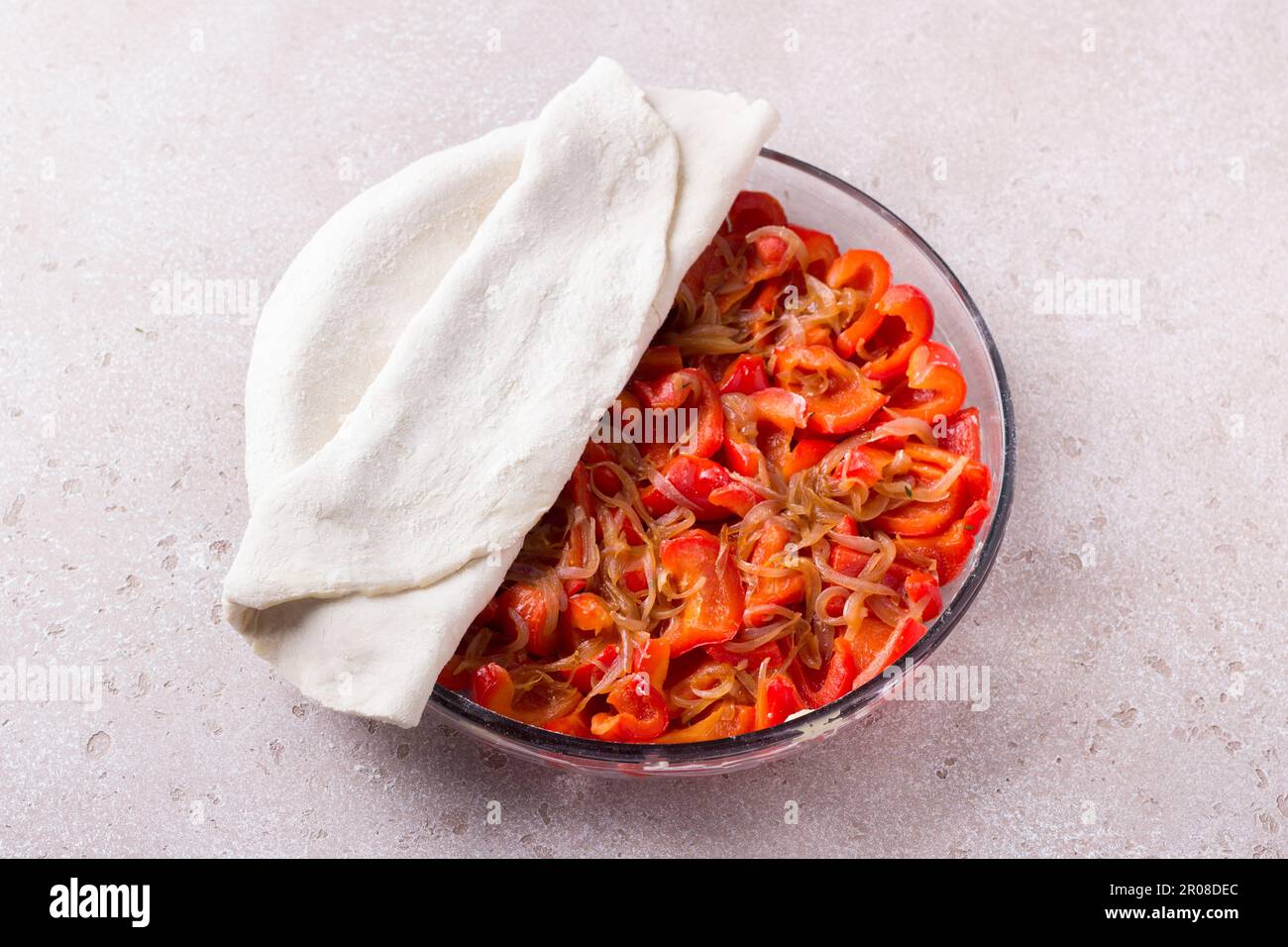 Glass form with red bell peppers, onions and spices half covered with ...