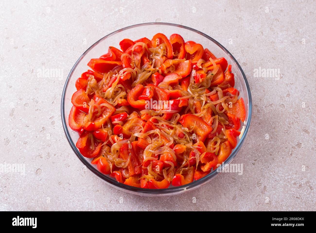 Glass form with stewed chopped red sweet pepper, onion, thyme and honey ...