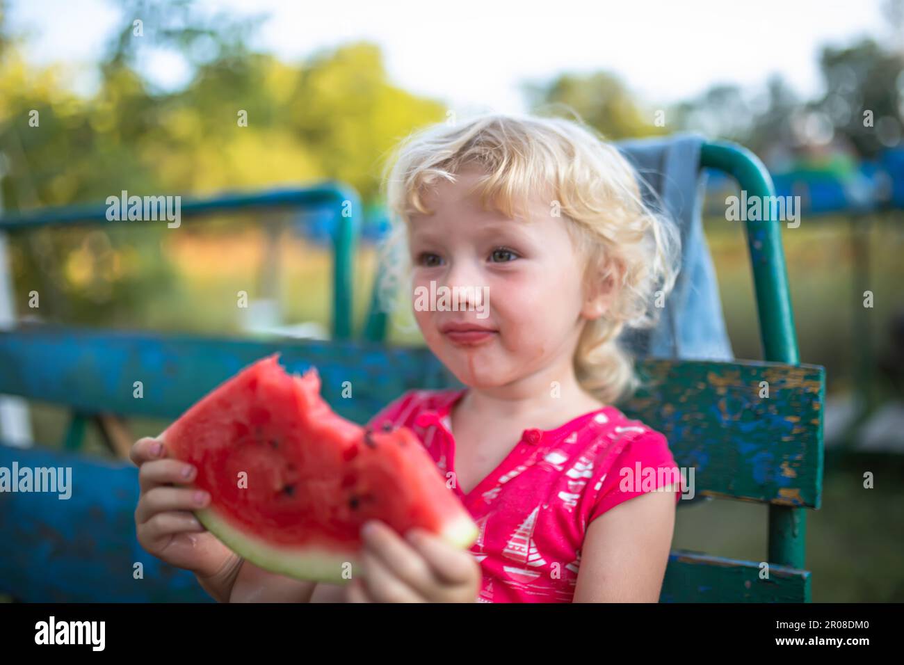 child in the backyard eats fresh watermelons. A girl reaches for a ...