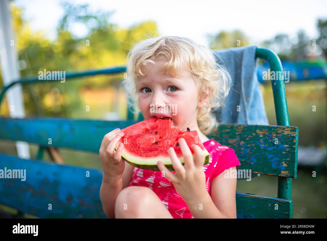 happy child with a slice of watermelon in his hands. Beautiful blonde ...