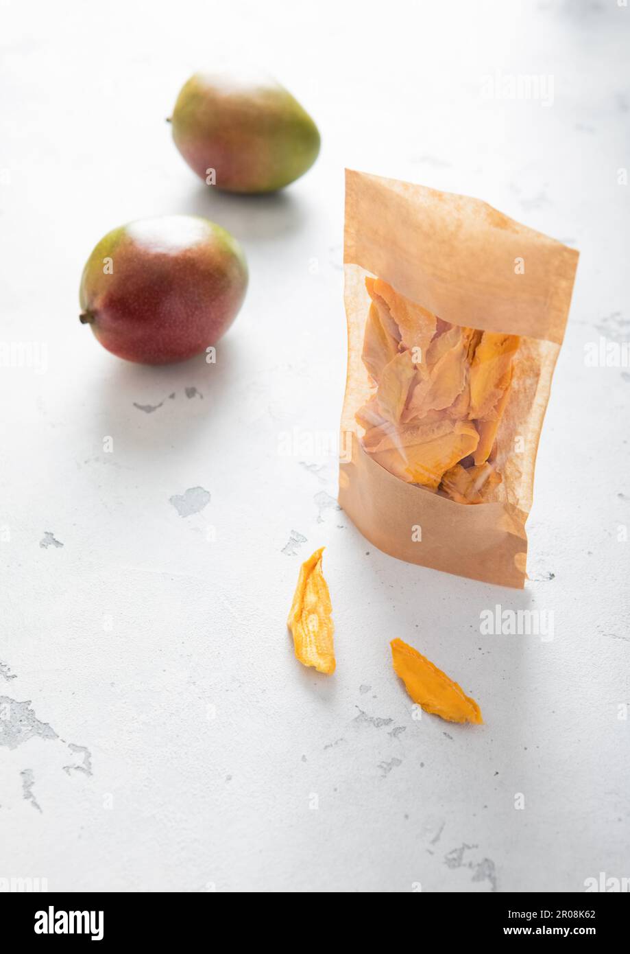 Pack of dried mango slices with two fresh raw mangoes. Top view Stock ...