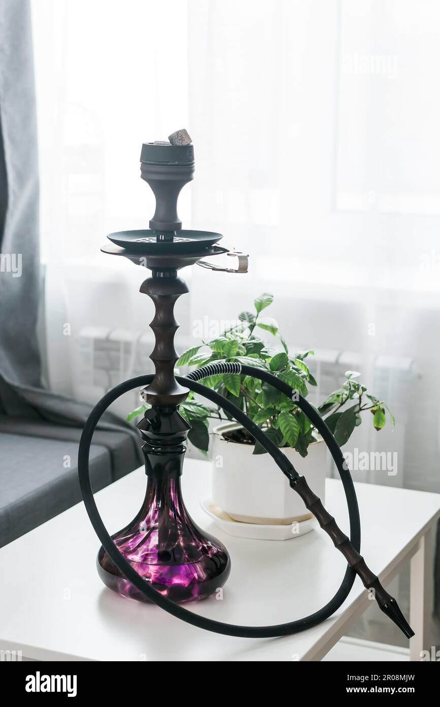 Hookah shisha with glass flask and metal bowl in room background ...