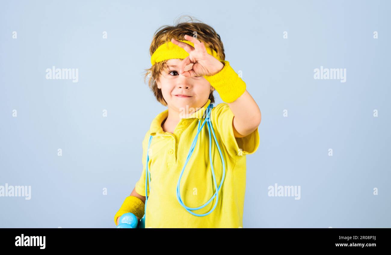 Fitness child in sportswear with jump rope and dumbbells showing ok ...