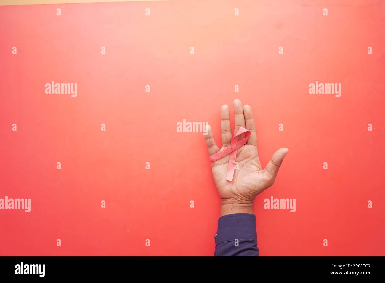 hand holding red HIV ribbon on red background top down Stock Photo - Alamy